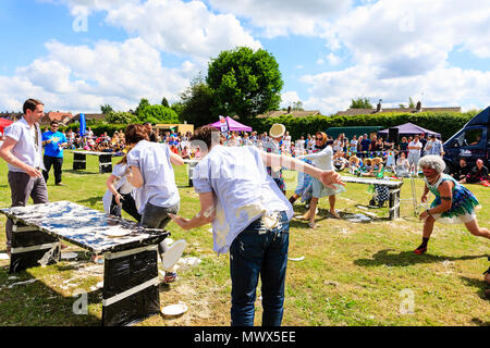 Two teams of four people throwing custard pies at each other at the ...