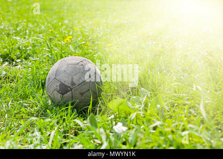 Old soccer ball forgotten in the green grass field. The football ...