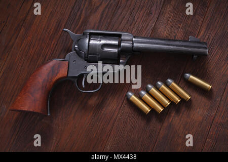 Old western revolver with cartridges on wooden table Stock Photo - Alamy