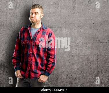 Young hipster man puffing cheeks with funny face. Mouth inflated with ...