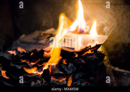 Sheets of white paper burning in a fire grate with small flames, smoke ...