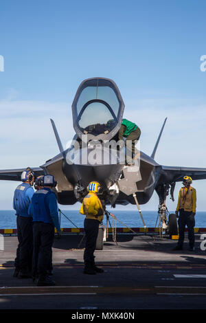 A flight deck crewman climbs down the ladder of an F/A-18A Hornet ...