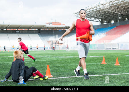 Coach giving instructions to children football team players during ...