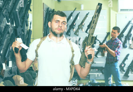 Two young men selecting air gun in military store Stock Photo - Alamy