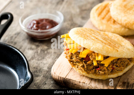 Arepa with shredded beef and cheese on wooden background. Venezuelan ...