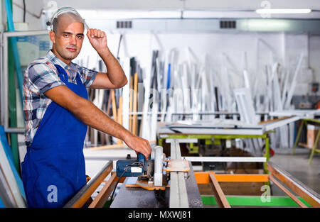 Confident friendly smiling workman ready to working on circular saw in ...