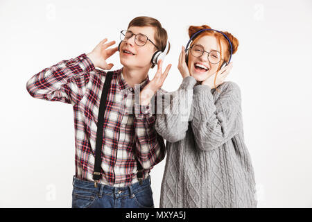 Happy couple of school nerds listening to music with headphones ...