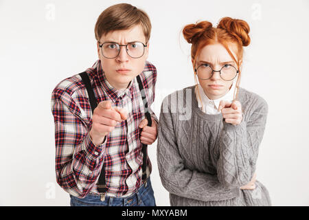 Angry couple of school nerds pointing pencils at camera isolated over ...