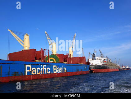 A large ocean-going cargo ship moves out to sea on calm waters. Dry ...