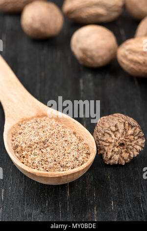 Nutmeg powder in a spoon with scattered nuts on wooden background Stock ...