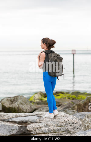 woman backpacker standing on rocks at the edge of the ocean Stock Photo ...
