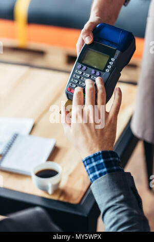 cropped shot of waiter holding payment terminal while smiling woman ...