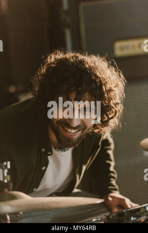 Handsome bearded man drummer sitting and plaing on drums over dark ...