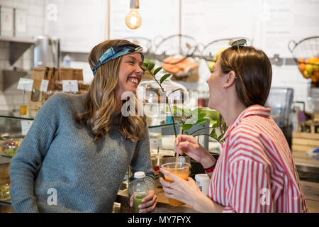 Two female friends laughing together in a cafe Stock Photo - Alamy