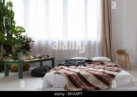 interior of a modern studio apartment with lots of plants and a bed on ...