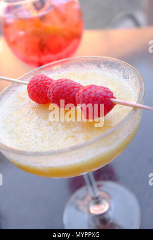 Alcoholic drink in a glass with a peach on a bright background. Summer ...