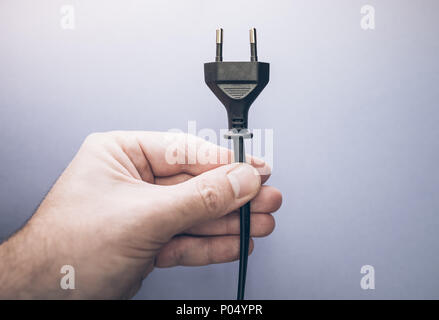 Hand holding an electrical outlet and a power cable Stock Photo - Alamy