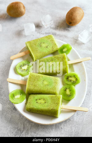 Popsicles from kiwi on plate over stone background with copy space. Top ...