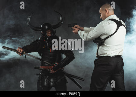 modern man aiming on samurai with gun while he taking out his sword ...
