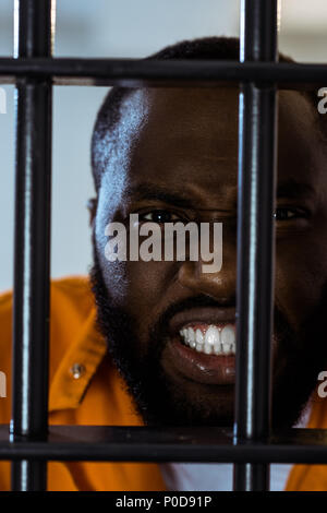 Prisoner behind bars looking angry and sad Stock Photo - Alamy