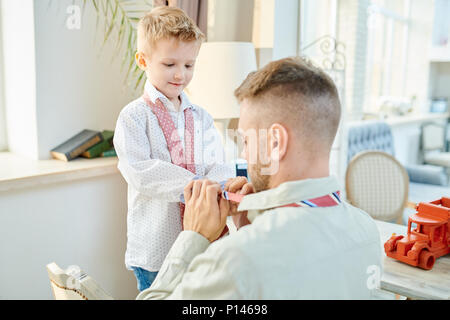 Father helping son binding his tie Stock Photo - Alamy