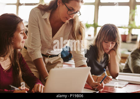 Girl helping a classmate in study in the classroom. High school girl in ...