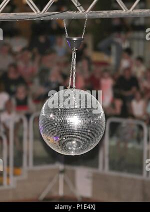 Big disco ball at the concert that reflects light directed at it in ...