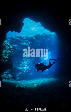 Scuba diver swims through tunnel Stock Photo - Alamy
