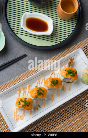 delicious Spice Ebi Maki roll on a wooden stand on a black insulated ...