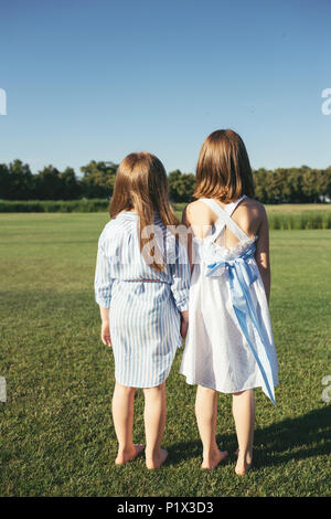 Girls sisters stand back to back confidently. Friendship support and ...