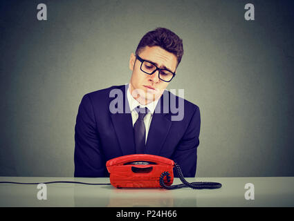 Desperate sad man waiting for someone to call him Stock Photo - Alamy