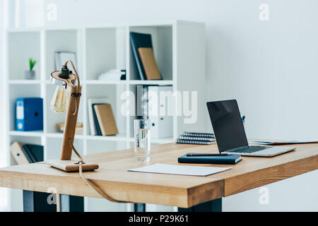 Stylish workplace with modern lamp and notebooks near light wall Stock ...