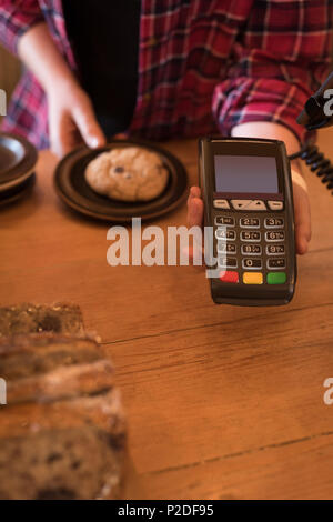 Mid section of woman holding payment terminal at counter Stock Photo ...