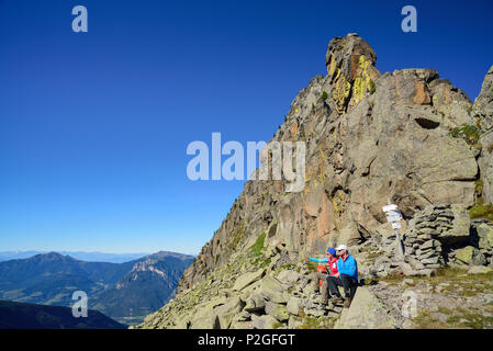Two hikers sitting beneath a rock spire and looking at a map, Trans ...