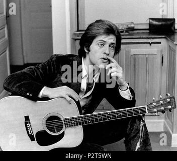 . American-born French singer Joe Dassin smoking a cigar at the table ...
