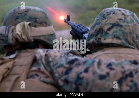 A Marine fires an M-249 squad automatic weapon from a fighting position ...