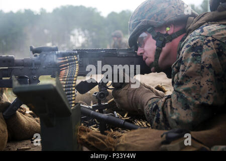 A Marine fires an M-249 squad automatic weapon from a fighting position ...