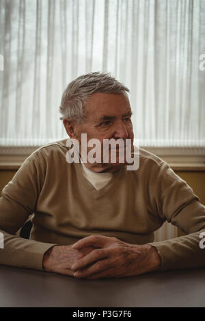 Senior man sitting at table Stock Photo - Alamy