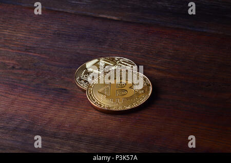 Two new golden physical bitcoins lies on dark wooden backgound, close ...