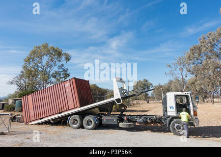 An old shipping container at a farm being hauled onto a Hino tipper ...