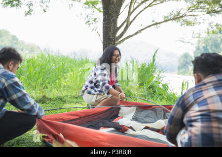 Friends setting up a tent by the lake for a weekend camping trip Stock ...