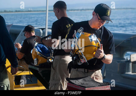 A diver prepares his diving equipment aboard the salvage ship USS ...