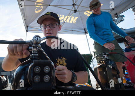 A diver prepares his diving equipment aboard the salvage ship USS ...