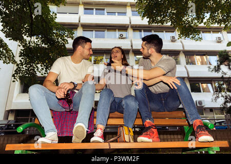 Positive three friends is talking while siiting on the bench Stock ...