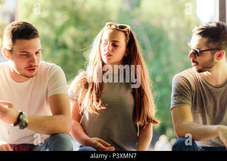 Positive three friends is talking while siiting on the bench Stock ...