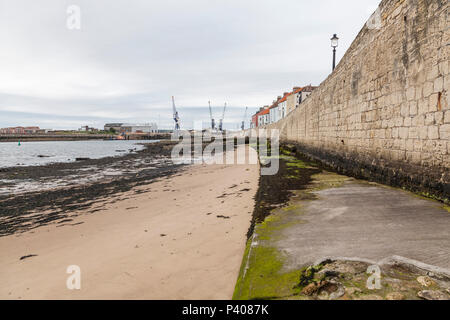 The beach,sea walls and houses with the cranes in the background at the ...
