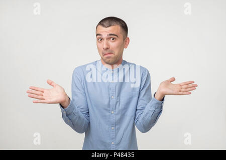Closeup portrait young man shrugging shoulders who cares so what I don ...