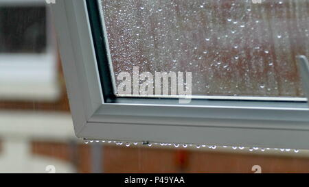 Large rain drops strike open window pane during heavy shower in England ...