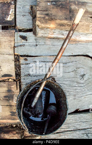 A bucket of black tar boils on the fire for use in repair and ...