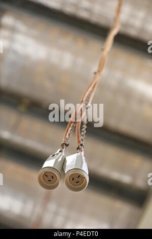 a pair of 3 pin power socket cord cable wire hanging from a factory ceiling roof. power supply ...